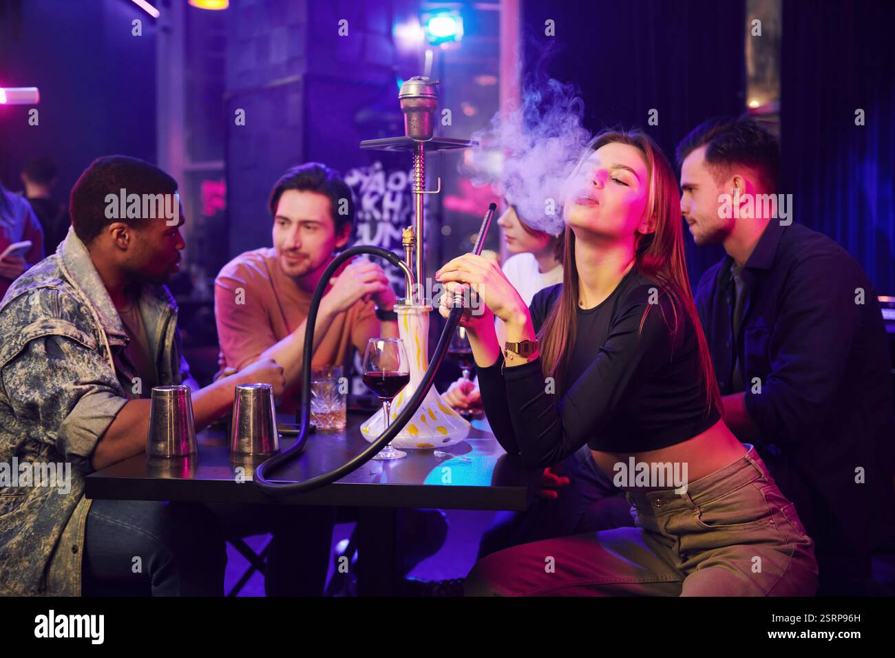 Hookah is on the table. Group of friends having fun in the night club ...