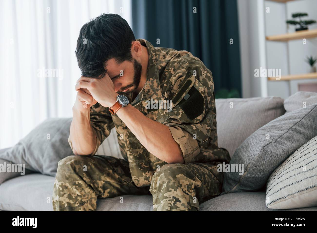 Post traumatic stress disorder. Soldier in uniform sitting indoors ...