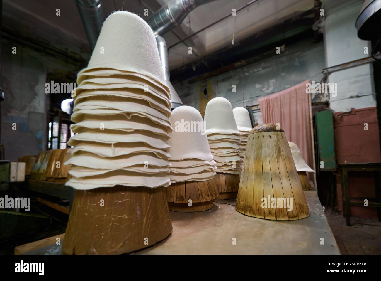 Layers of felt hats awaiting craftsmanship in a vintage workshop, where ...