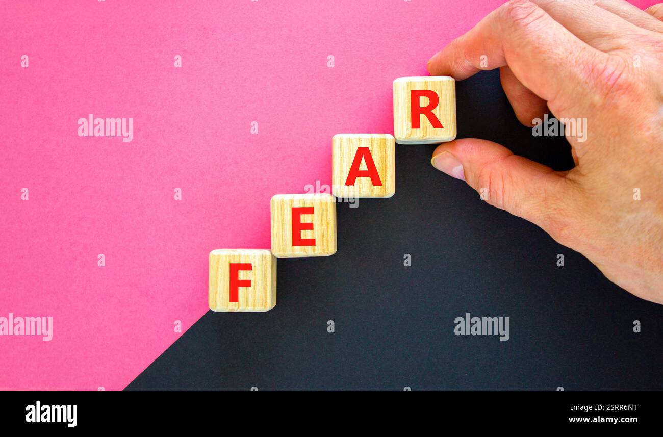 Fear symbol. Concept word Fear on beautiful wooden blocks. Businessman hand. Beautiful black and ...