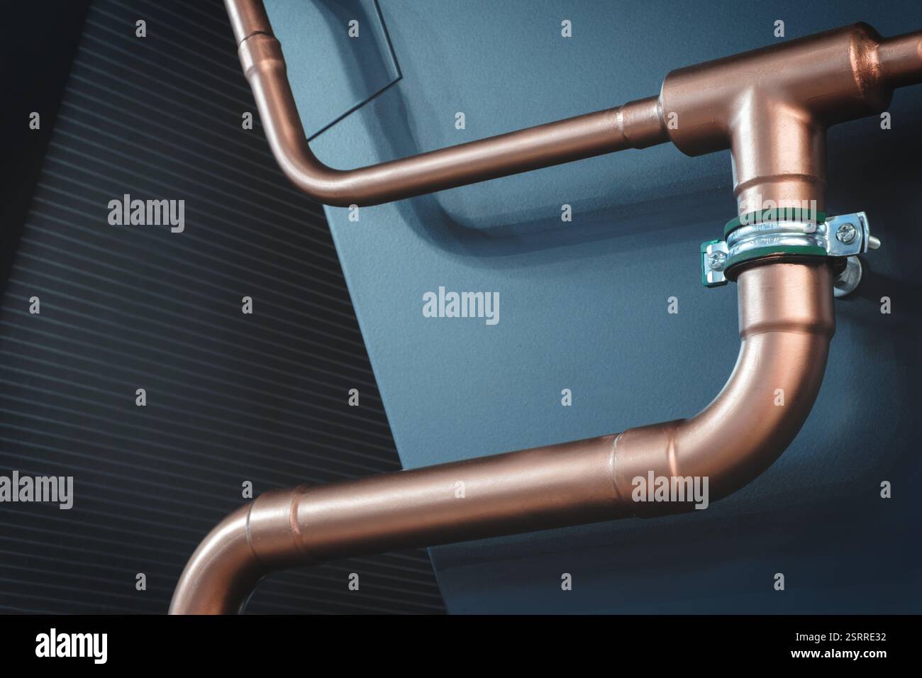 pipe is made of copper and is curved. The pipe is attached to the wall ...