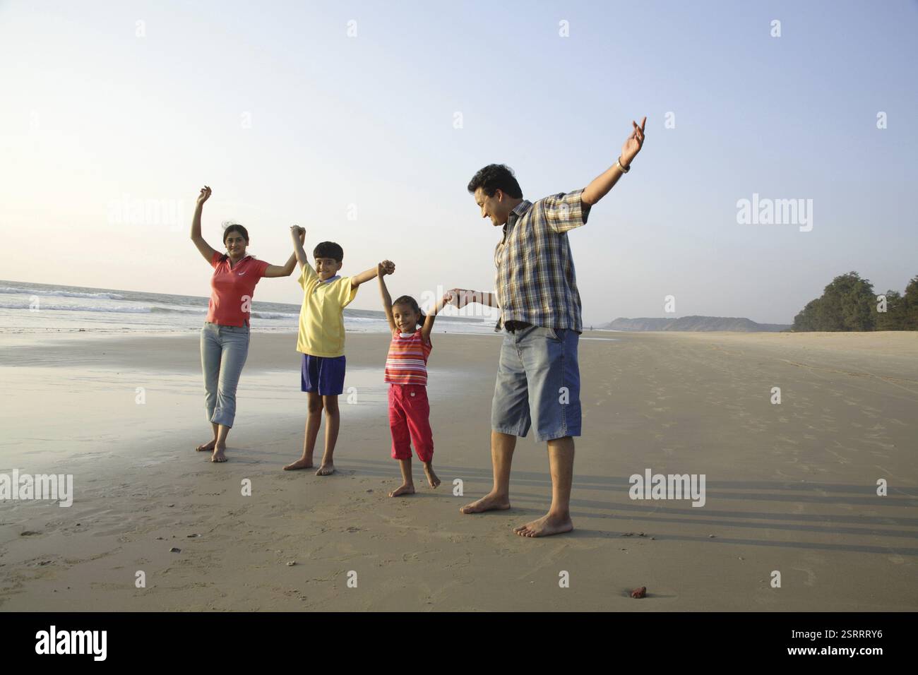 South Asian Indian parent and children holding hands up standing ...