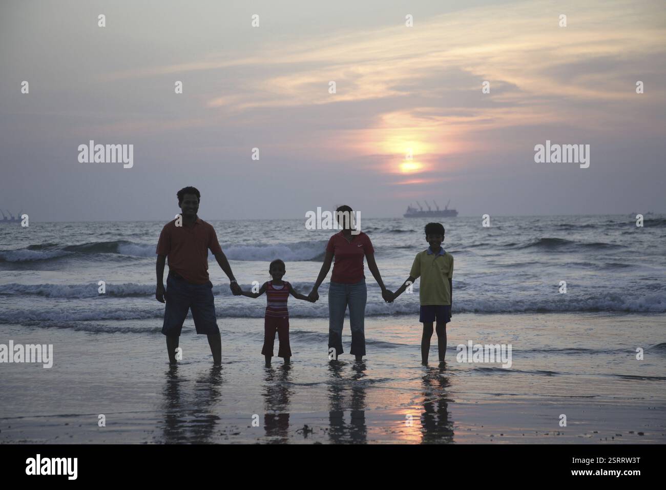South Asian Indian parent and children holding hands looking at golden ...