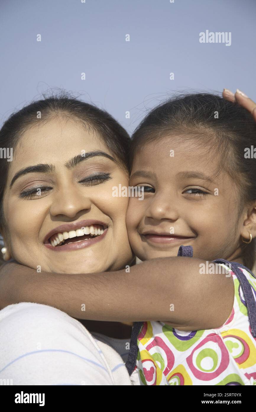 South Asian Indian daughter sitting on lap of mother hugging each other ...