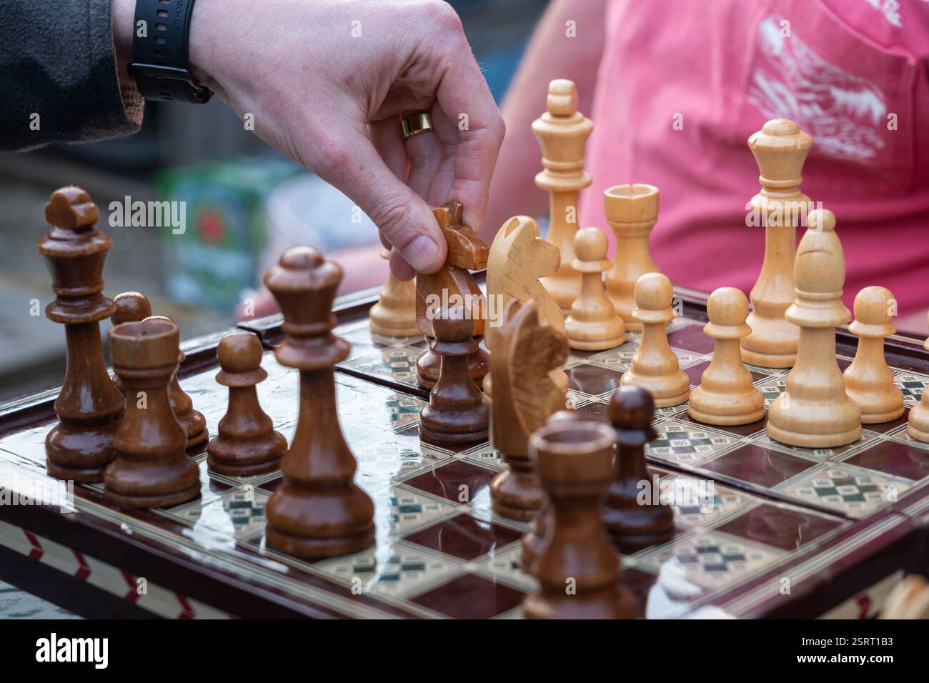 Two men playing chess outdoors face to face with a wooden chess board ...
