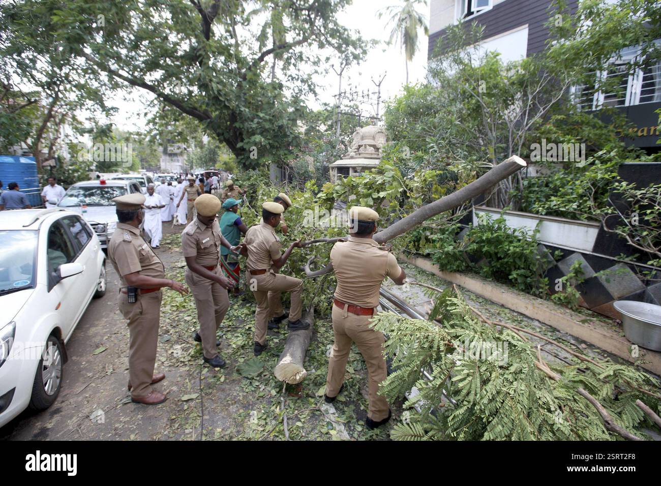 Chennai police personnel remove uprooted trees that came in the path of ...