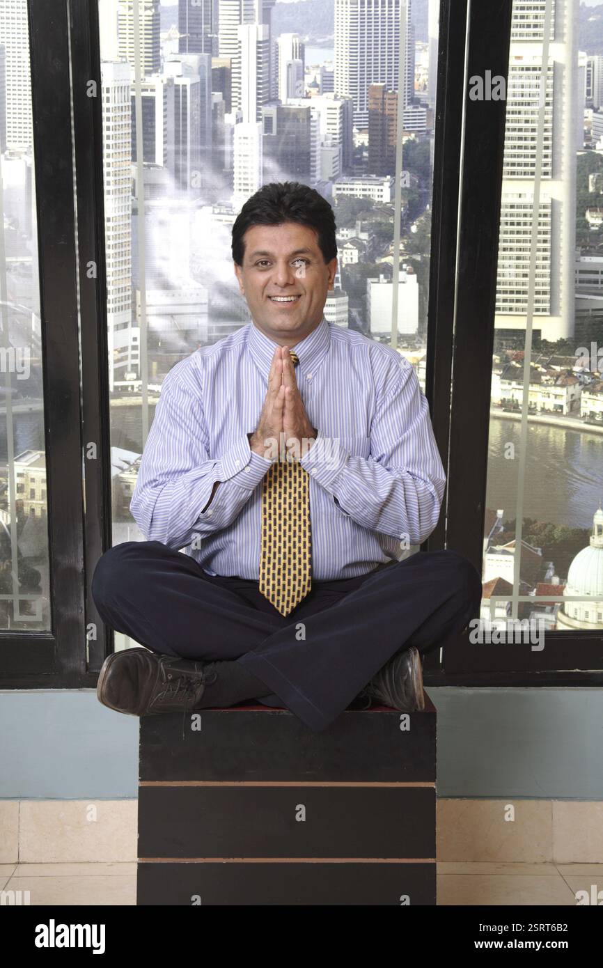 Executive sitting on small table with pose of Namaste in office at top ...
