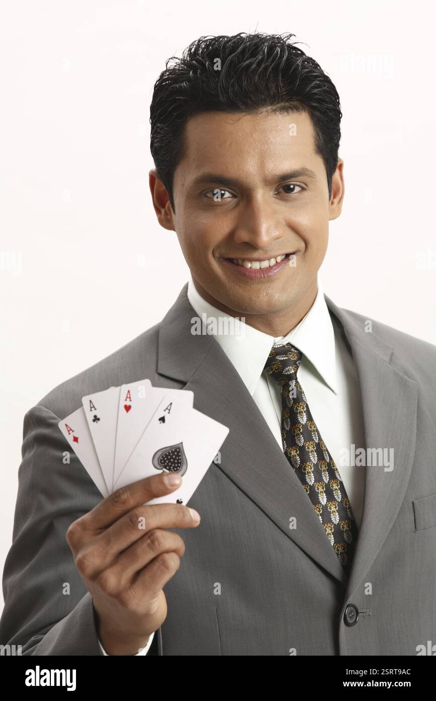 Businessman holding four aces of playing cards in his thumb index and ...