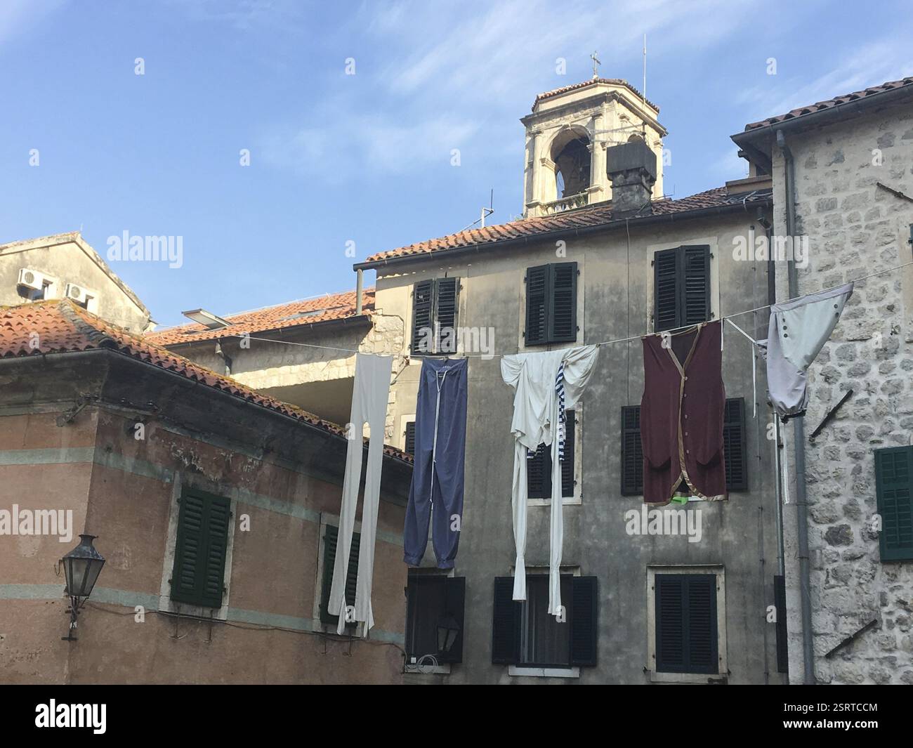 Laundry hanging in front of historic buildings with red tiled roofs in ...