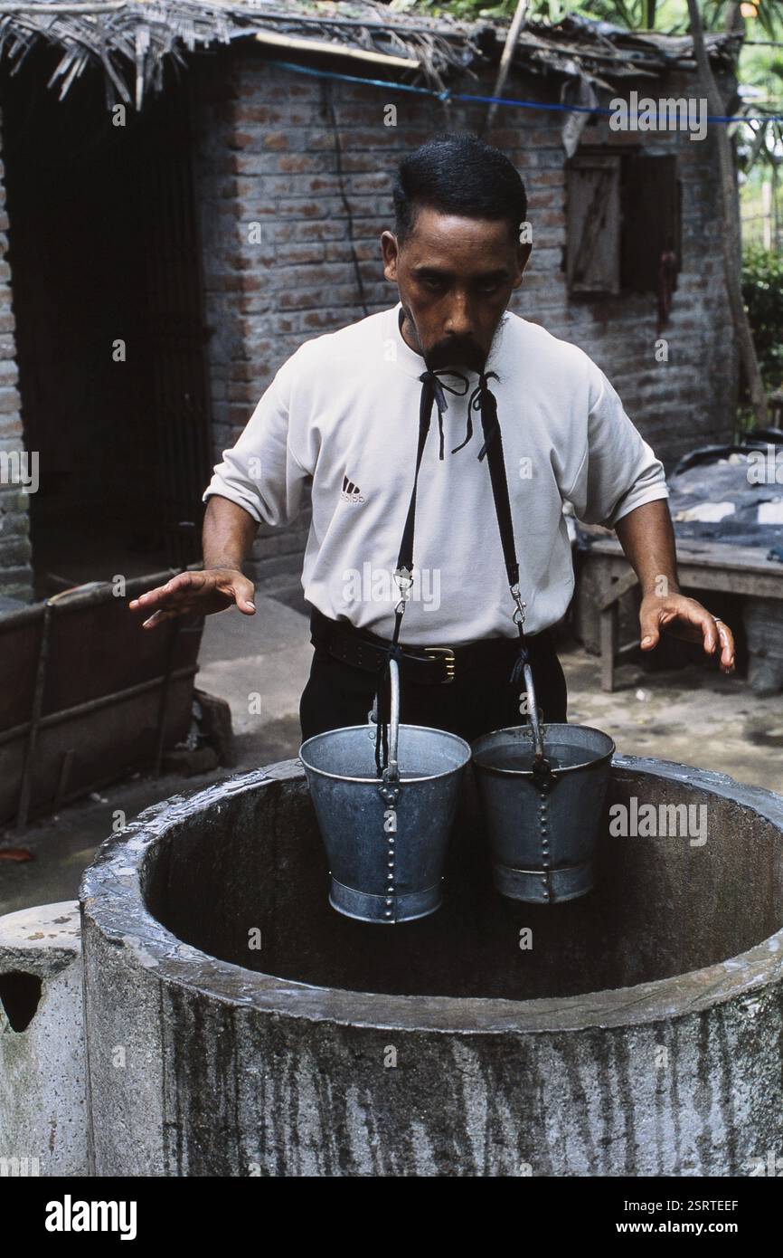 Sailendra Nath Roy holding buckets of water with his moustache, India ...