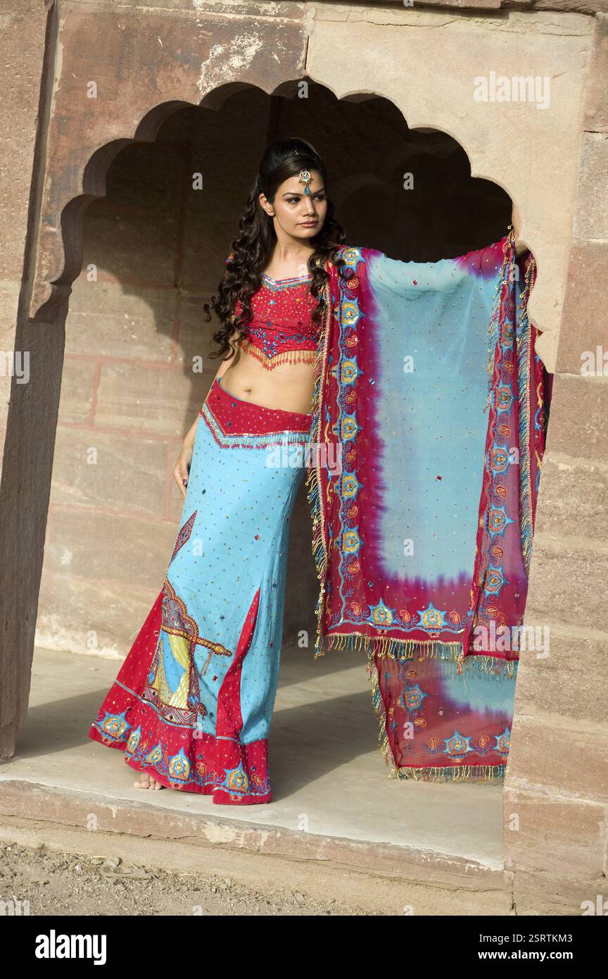 Lady in traditional wearing standing at heritage arch, India MR#746B ...