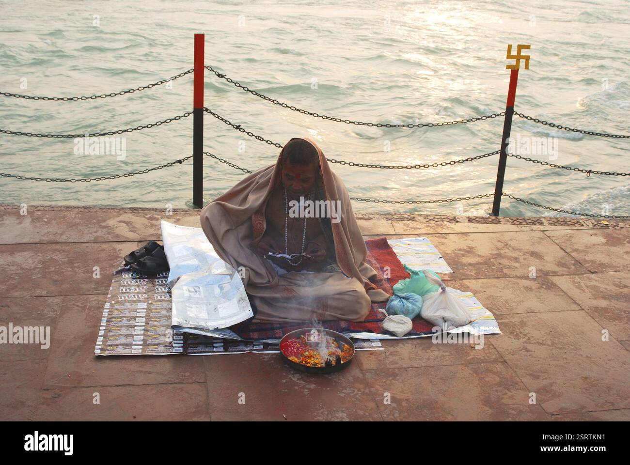 Man reading scriptures on bank of river ganga ganges at har ki pouri in ...