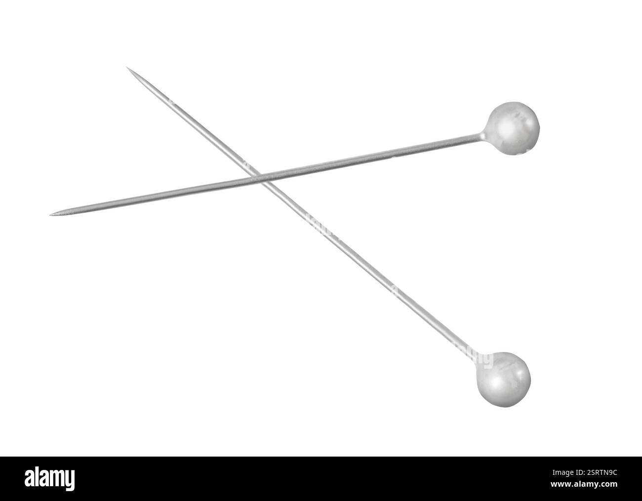 Two crossed metal pins with round heads lying on a white background ...