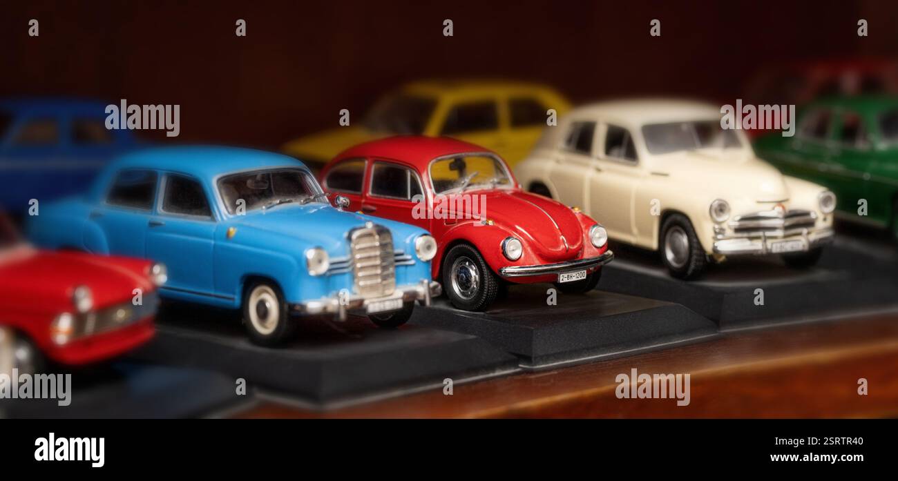 Colorful miniature vintage cars are displayed on a wooden shelf ...