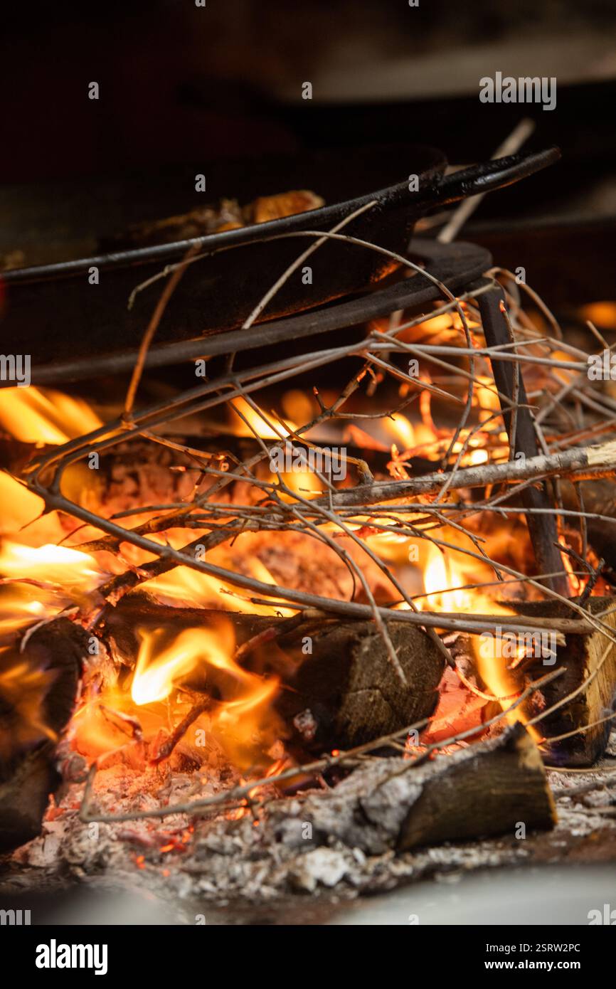 Close-up shot of a traditional wood-fired paella cooker, with flames ...