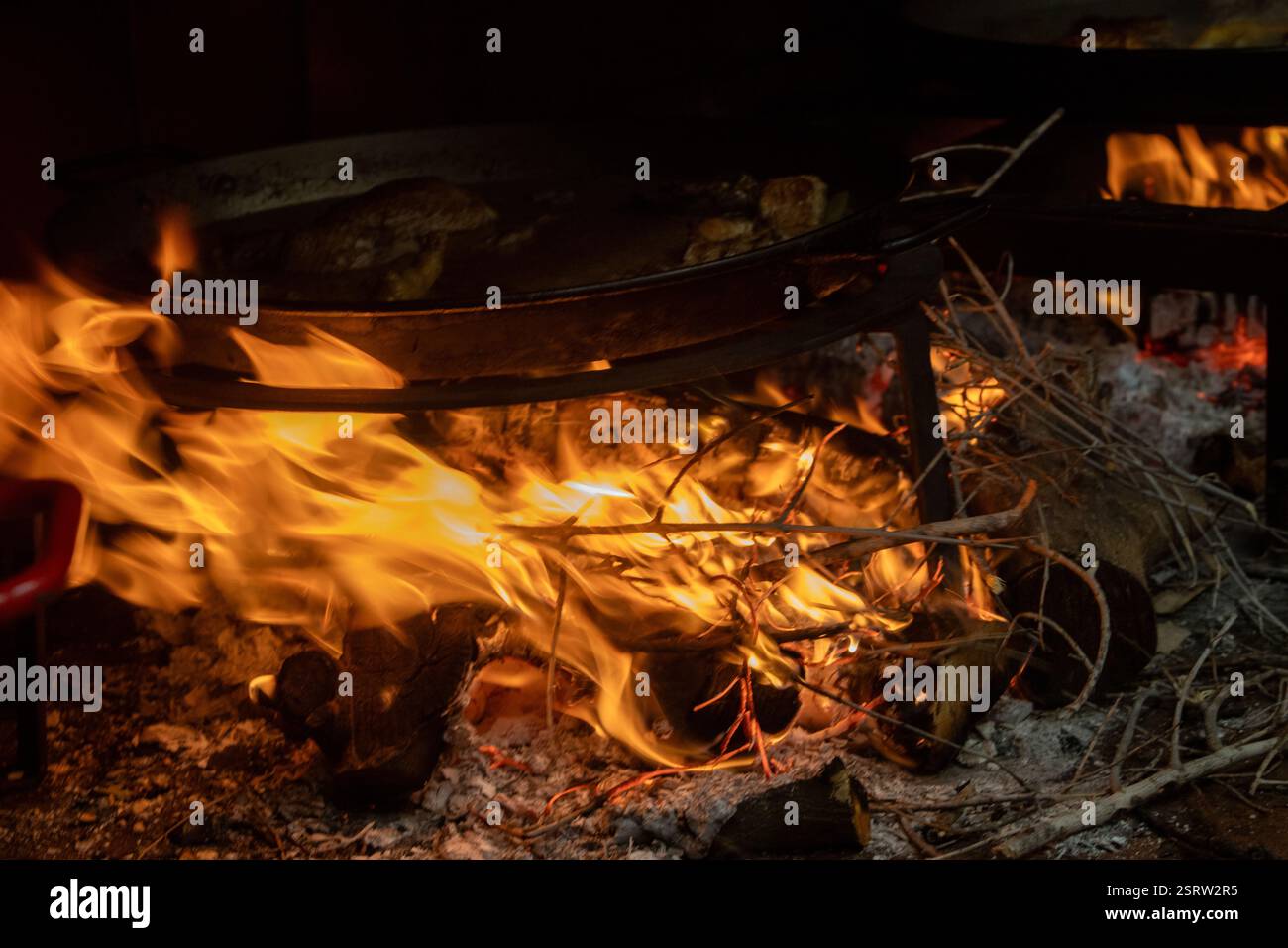 Close-up shot of a traditional wood-fired paella cooker, with flames ...