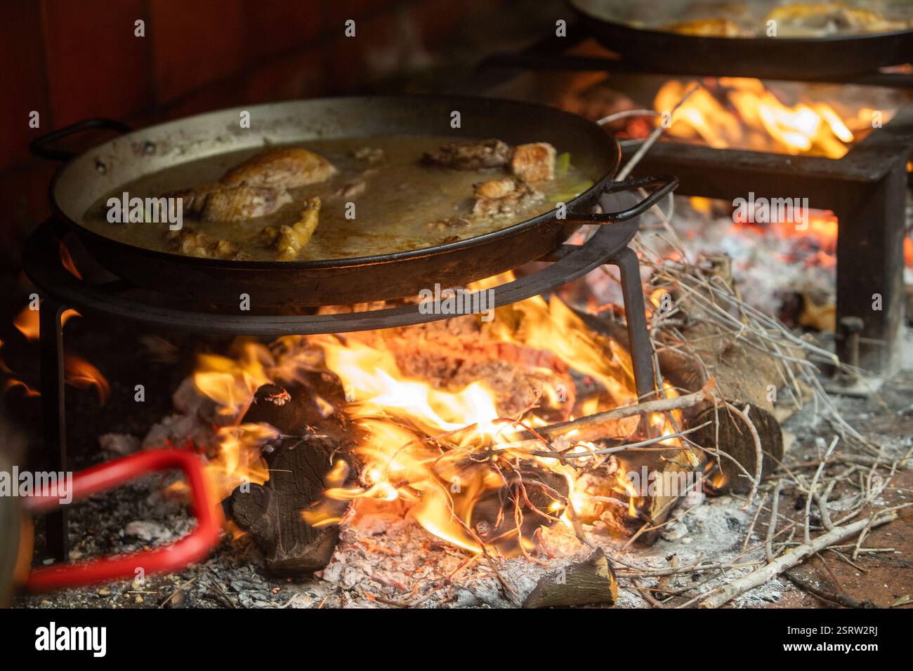 Close-up shot of a traditional wood-fired paella cooker, with flames ...