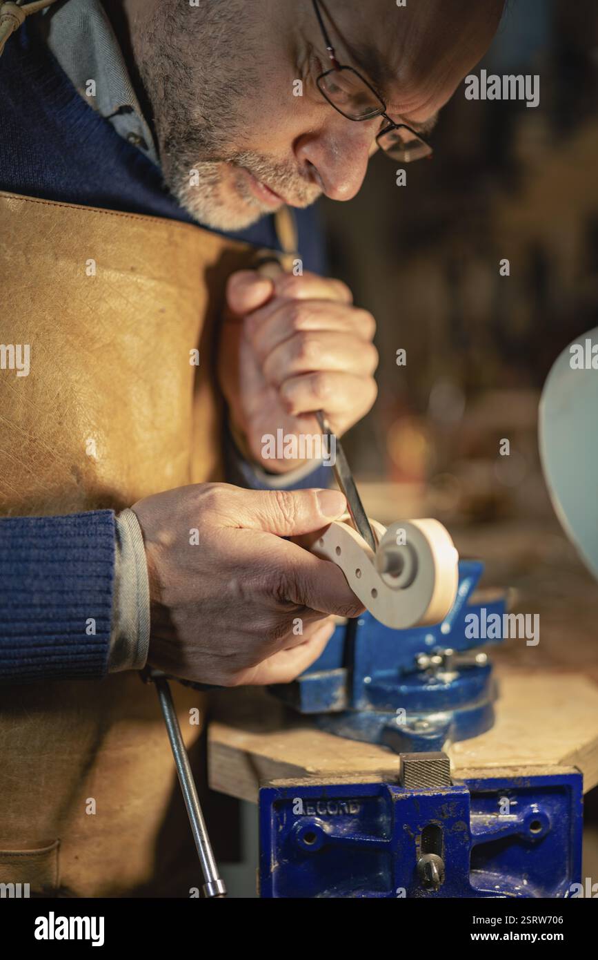 Italian luthier is meticulously carving the scroll of a violin using a ...