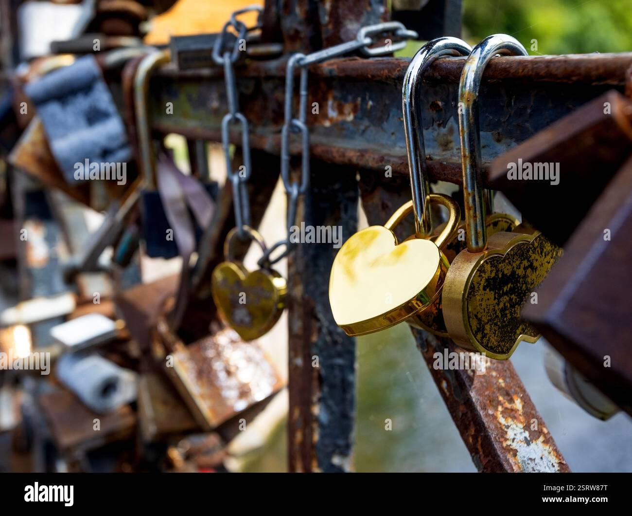 Heart-shaped padlocks attached to a rusty bridge railing, symbolizing ...