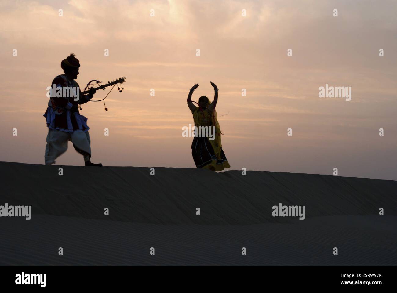 Folk musician playing ravanhatta and dancer dancing on sand dune at ...