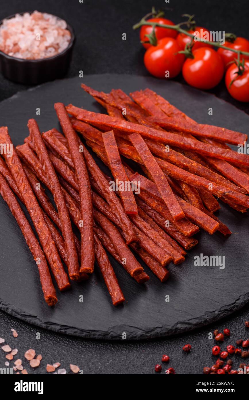 Jerky dried fish sticks with salt and spices on a dark concrete ...
