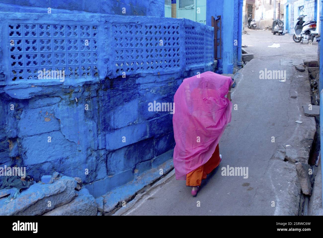 Girl in pink odhani walking in narrow lane of brahmapuri near a blue ...