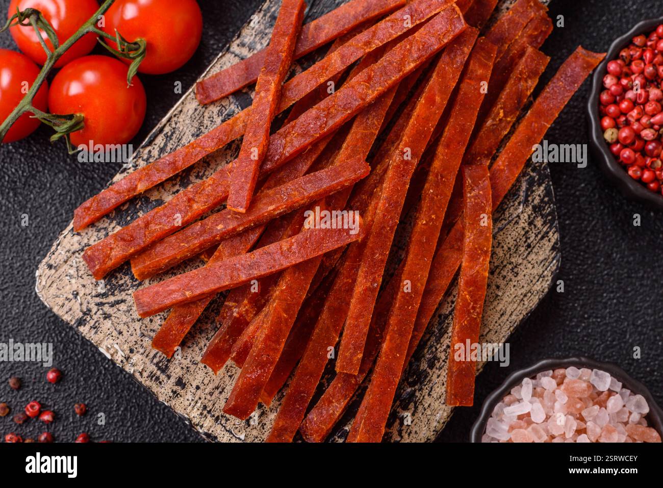 Jerky dried fish sticks with salt and spices on a dark concrete ...