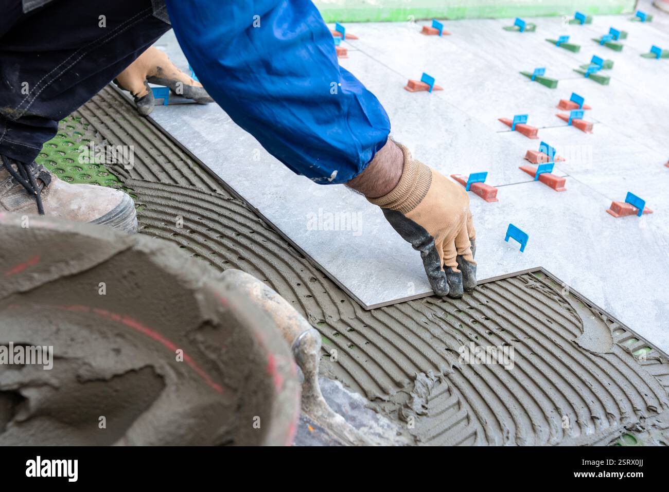 Bricklayer tiler places tiles of a new floor on the glue. Construction ...