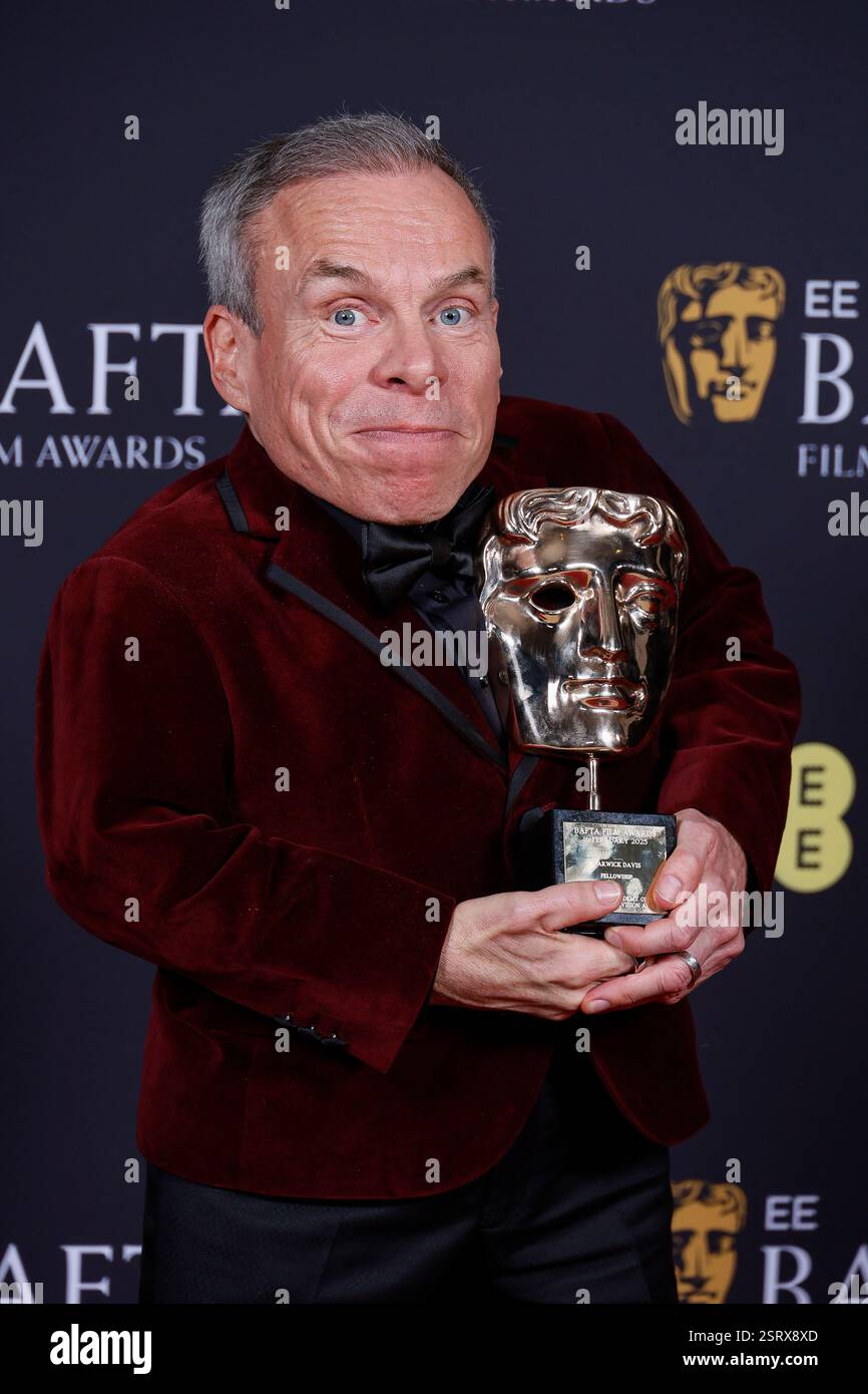 Warwick Davis poses with the BAFTA fellowship award at the 78th British ...