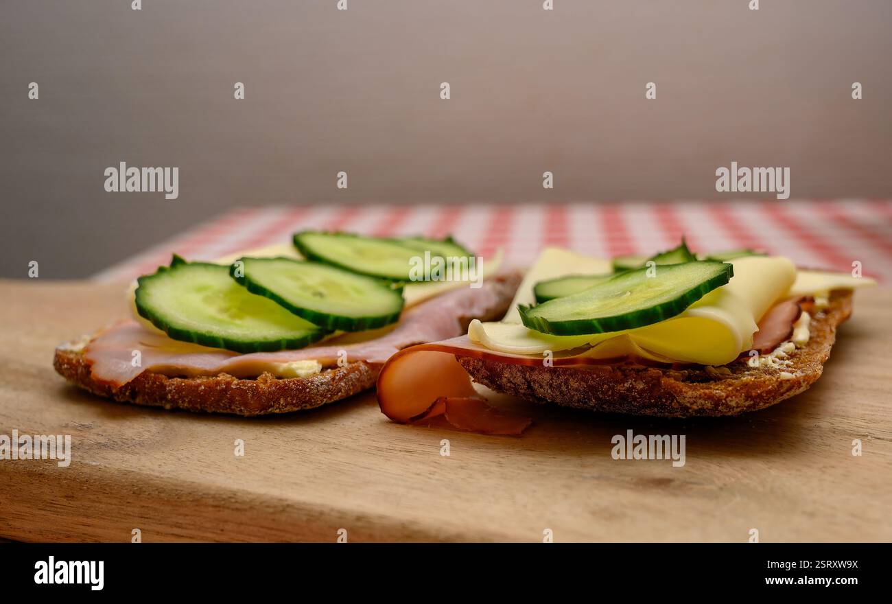 Two open-faced sandwiches feature slices of ham, cheese, and fresh ...