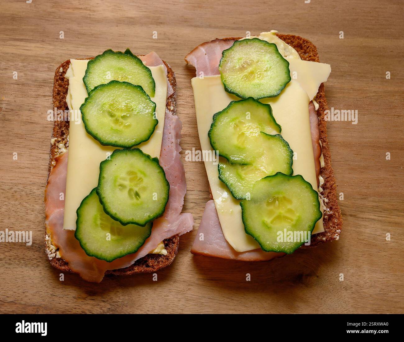 Two open-faced sandwiches feature slices of ham, cheese, and fresh ...