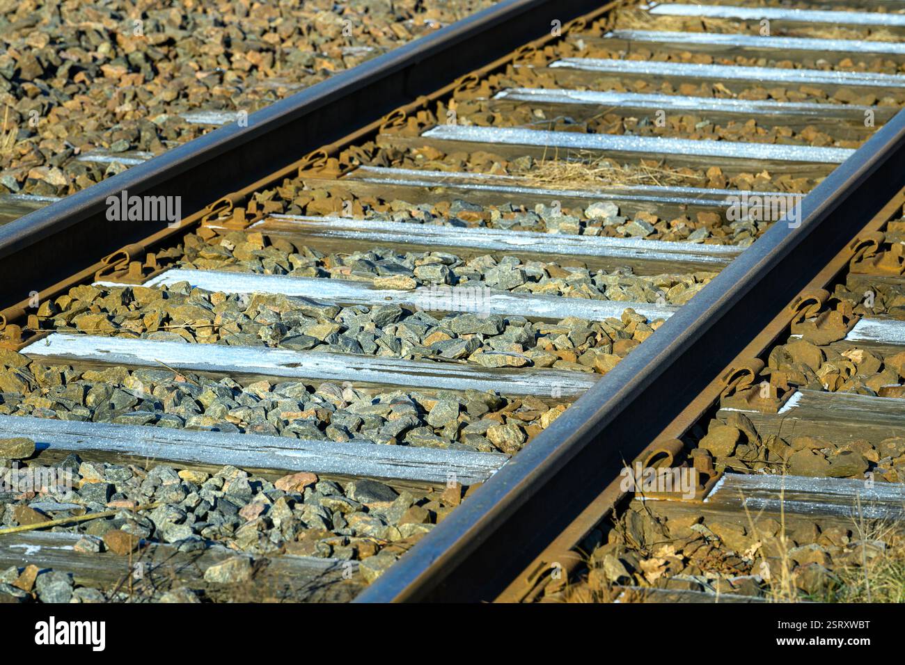 Metal railway tracks are lined with gravel, stretching across the ...