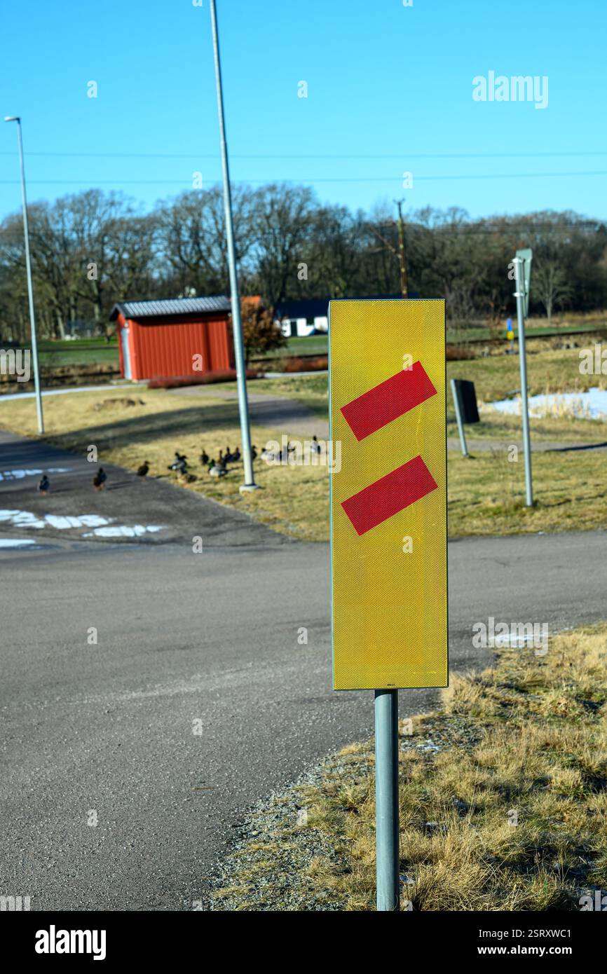 A bright yellow road sign with red chevrons alerts drivers closing ...
