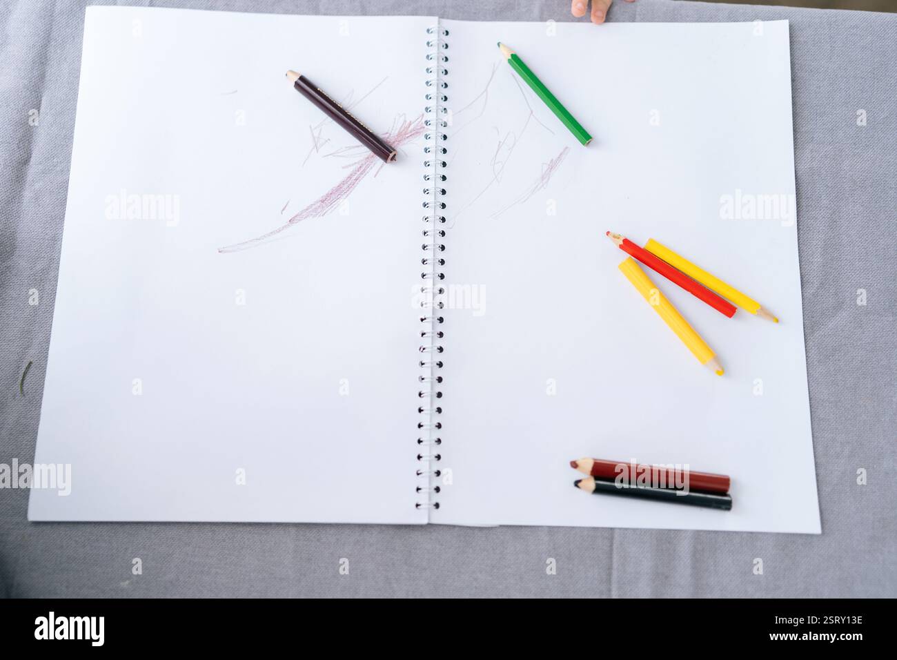 Top view of colorful pencil strokes scattered across open sketchbook, surrounding drawing tools ...