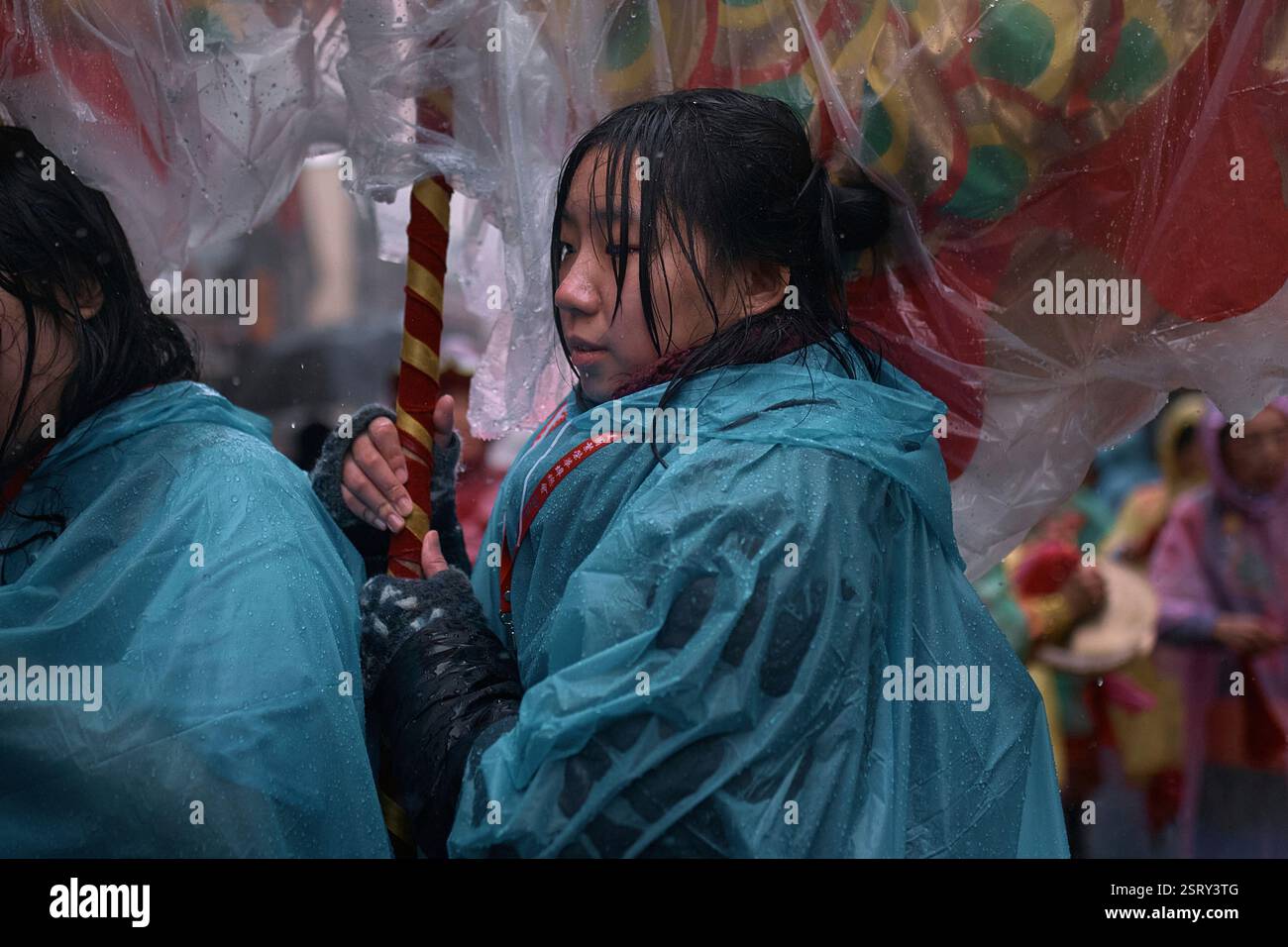 Parade goers march under the rain carrying a dragon during the Chinese ...