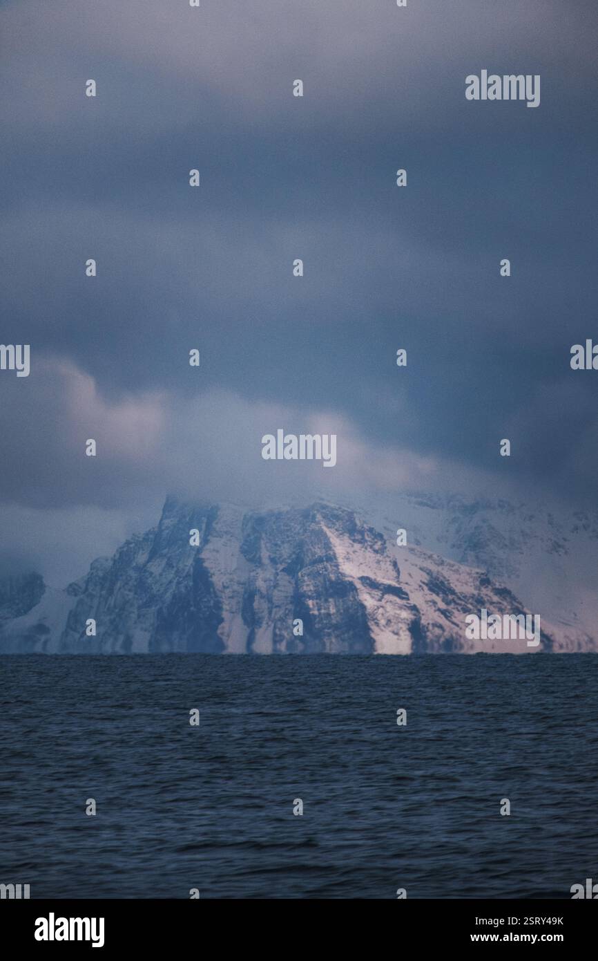 Distant rocky snowy mountains under grey clouds, the Lyngen Alps ...