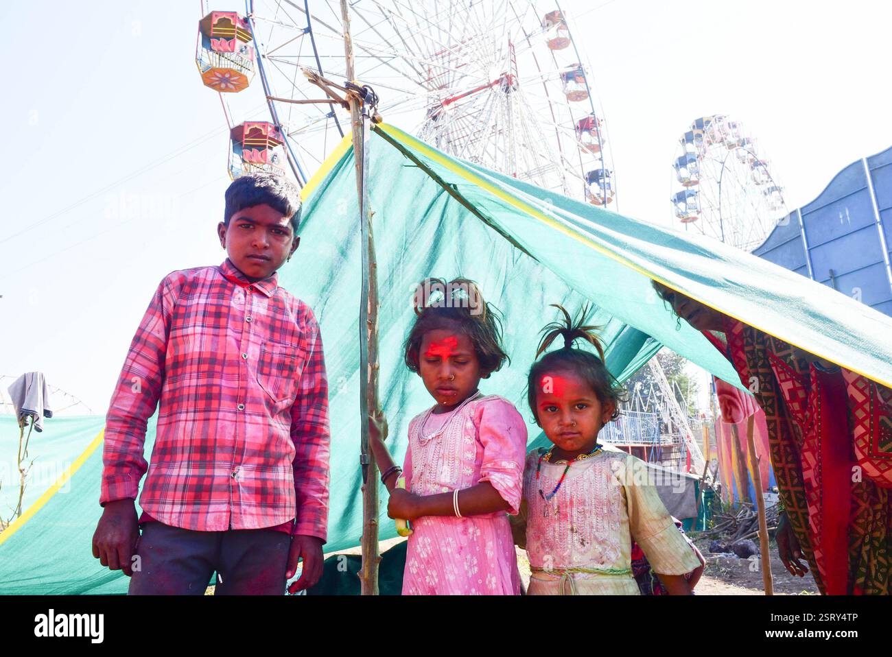 Children pose for a photo in the foreground of festival area. Pilgrims ...