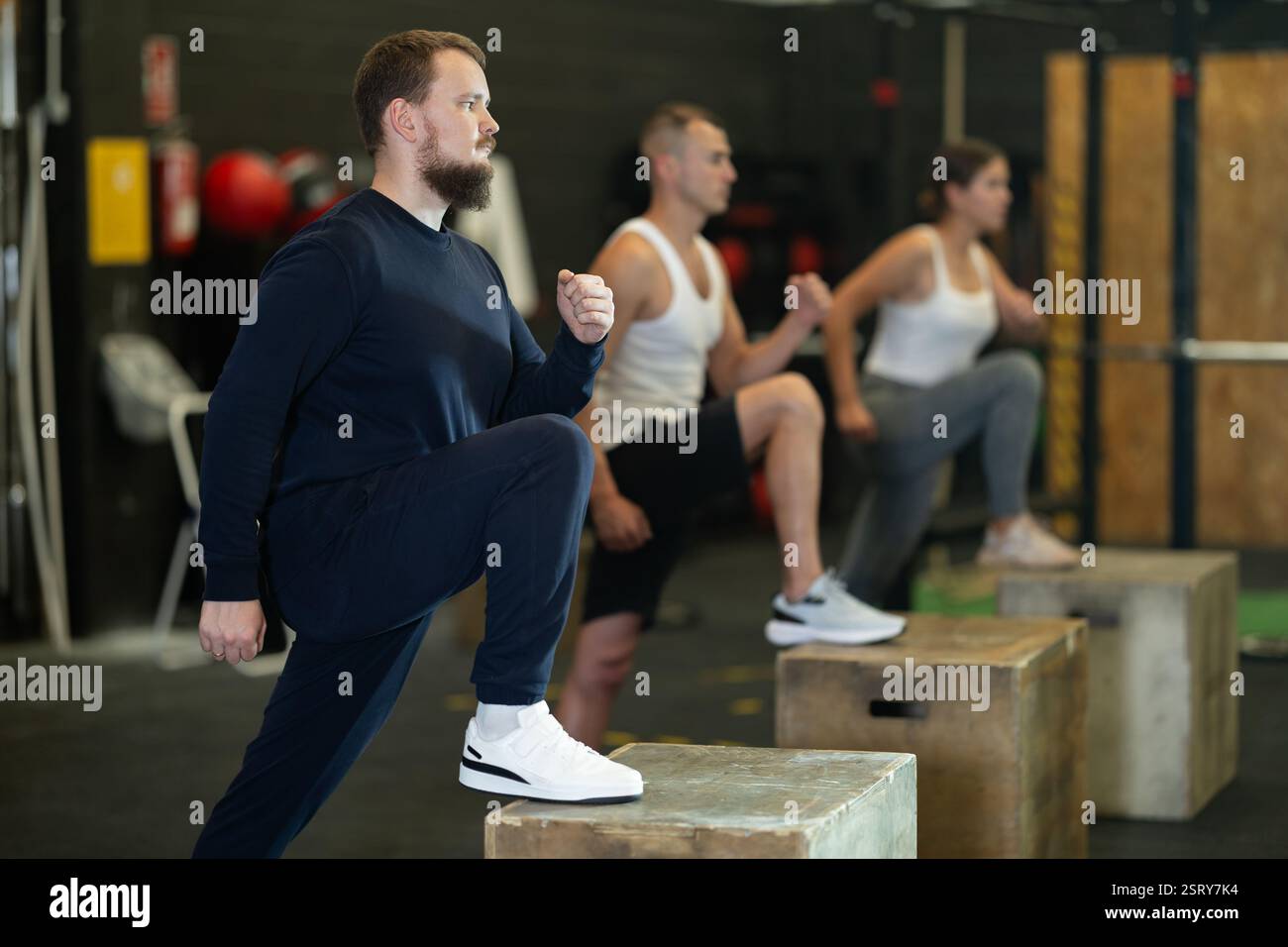 Young bearded man doing box step-ups in group interval training Stock ...