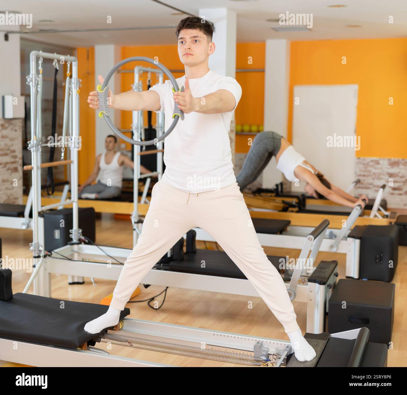 Guy performing pilates exercises with resistance ring on reformer Stock ...