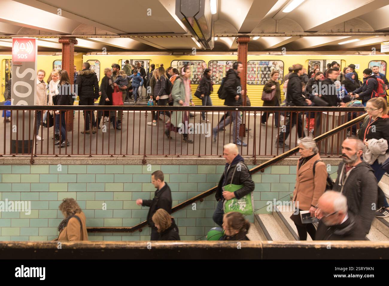 Commuters at Berlin U-Bahn station (likely Hauptbahnhof). Yellow train ...