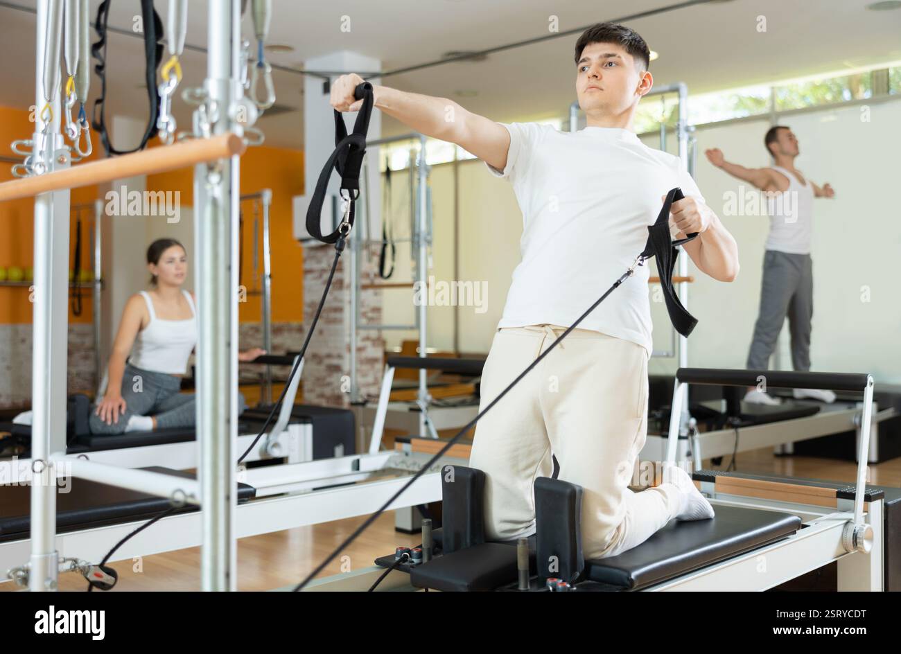 Guy doing exercises with straps in arms on Pilates reformer Stock Photo ...