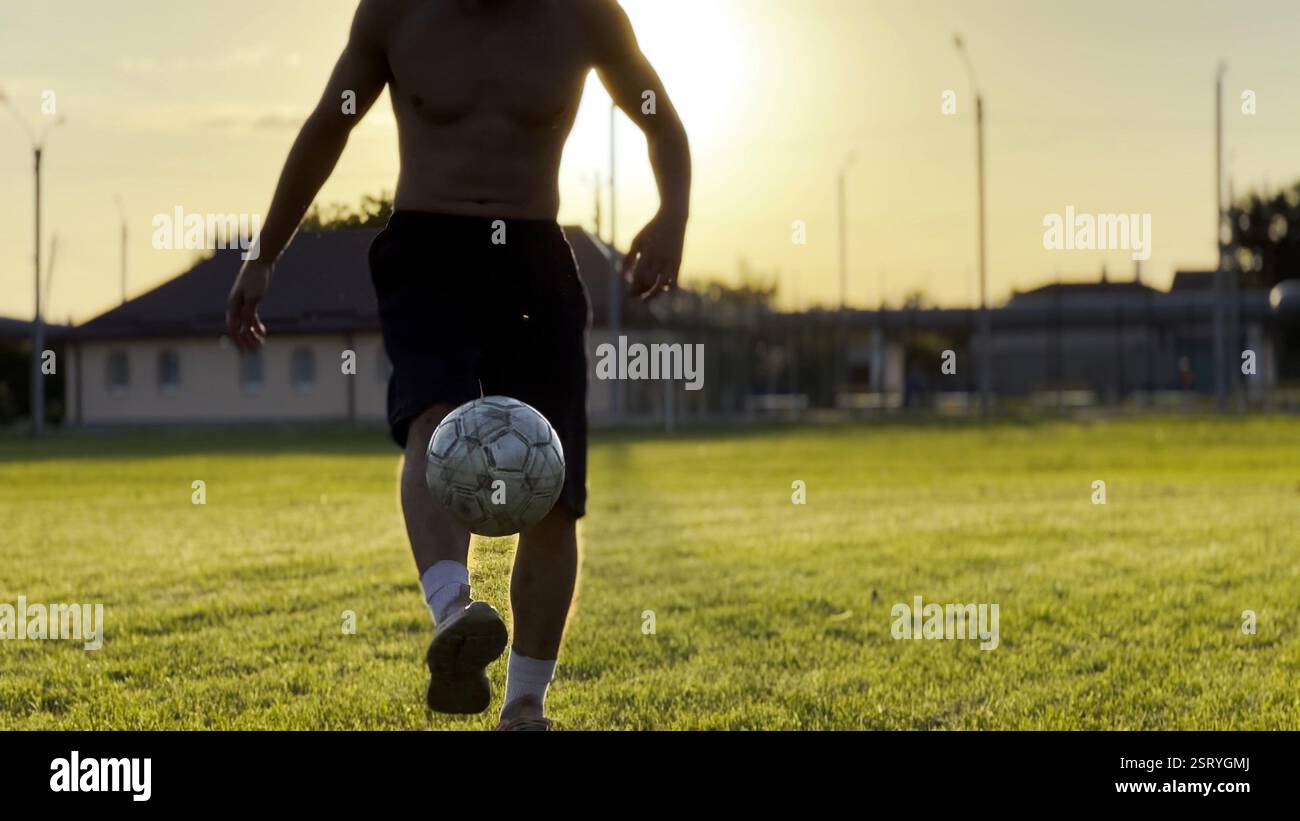 Male feet of professional footballer kicking ball at green field. Legs ...