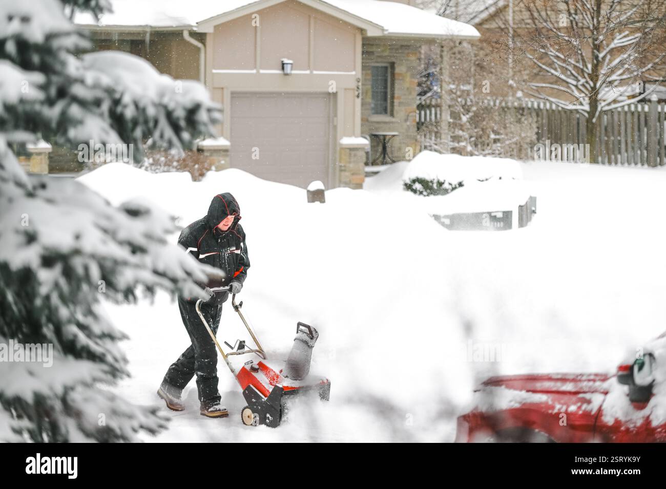 winter snow storm clean up - a man uses the snow blower to move snow ...