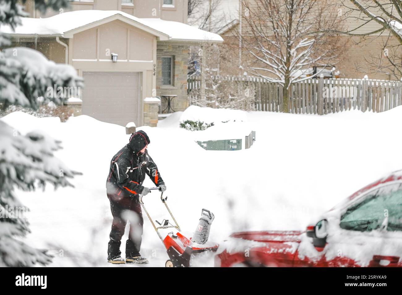 winter snow storm clean up - a man uses the snow blower to move snow ...