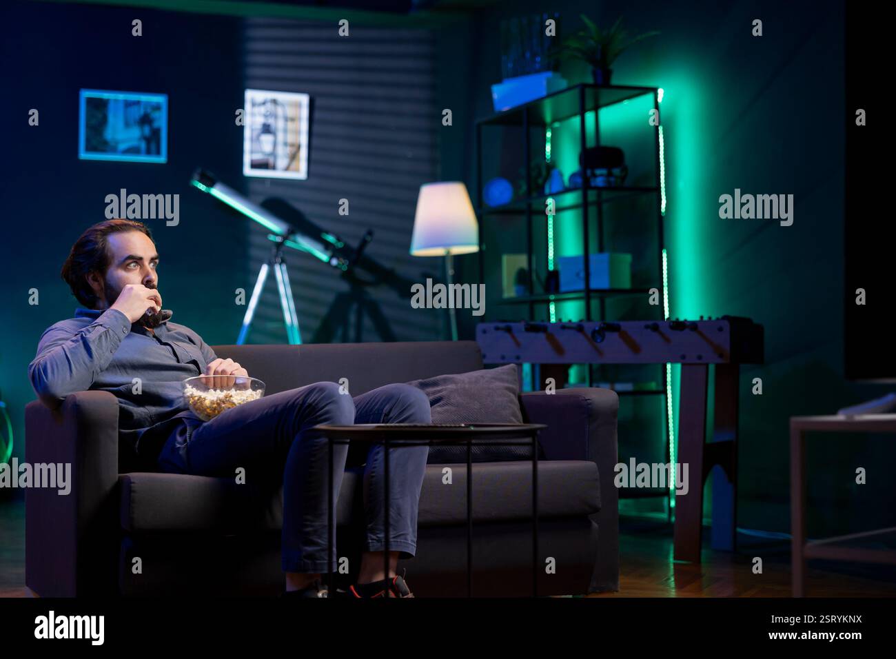 Man in apartment watching horror movie broadcasted on TV, shocked by ...