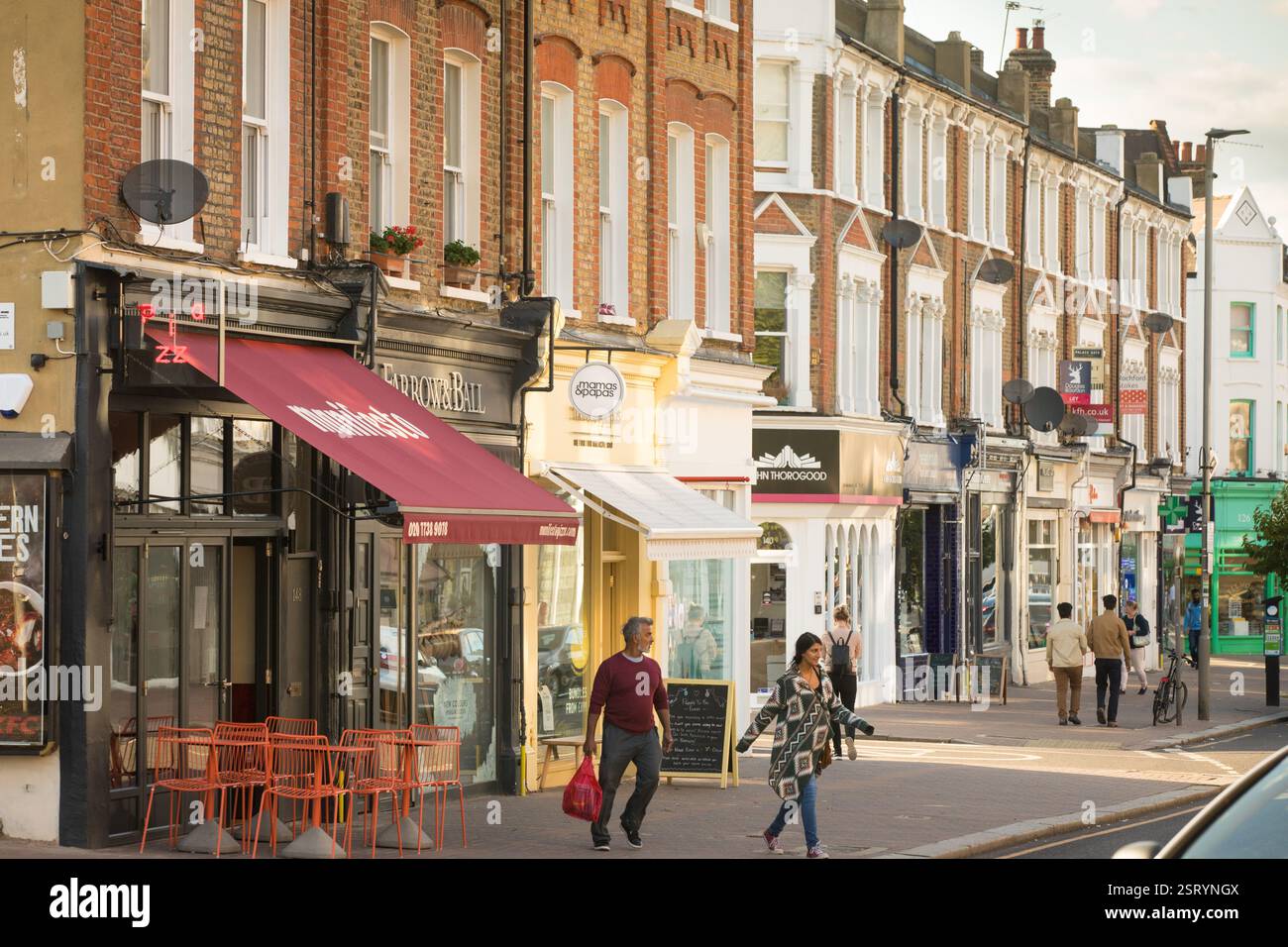 Pedestrians walk along shops on Northcote Road, London, UK. Victorian ...