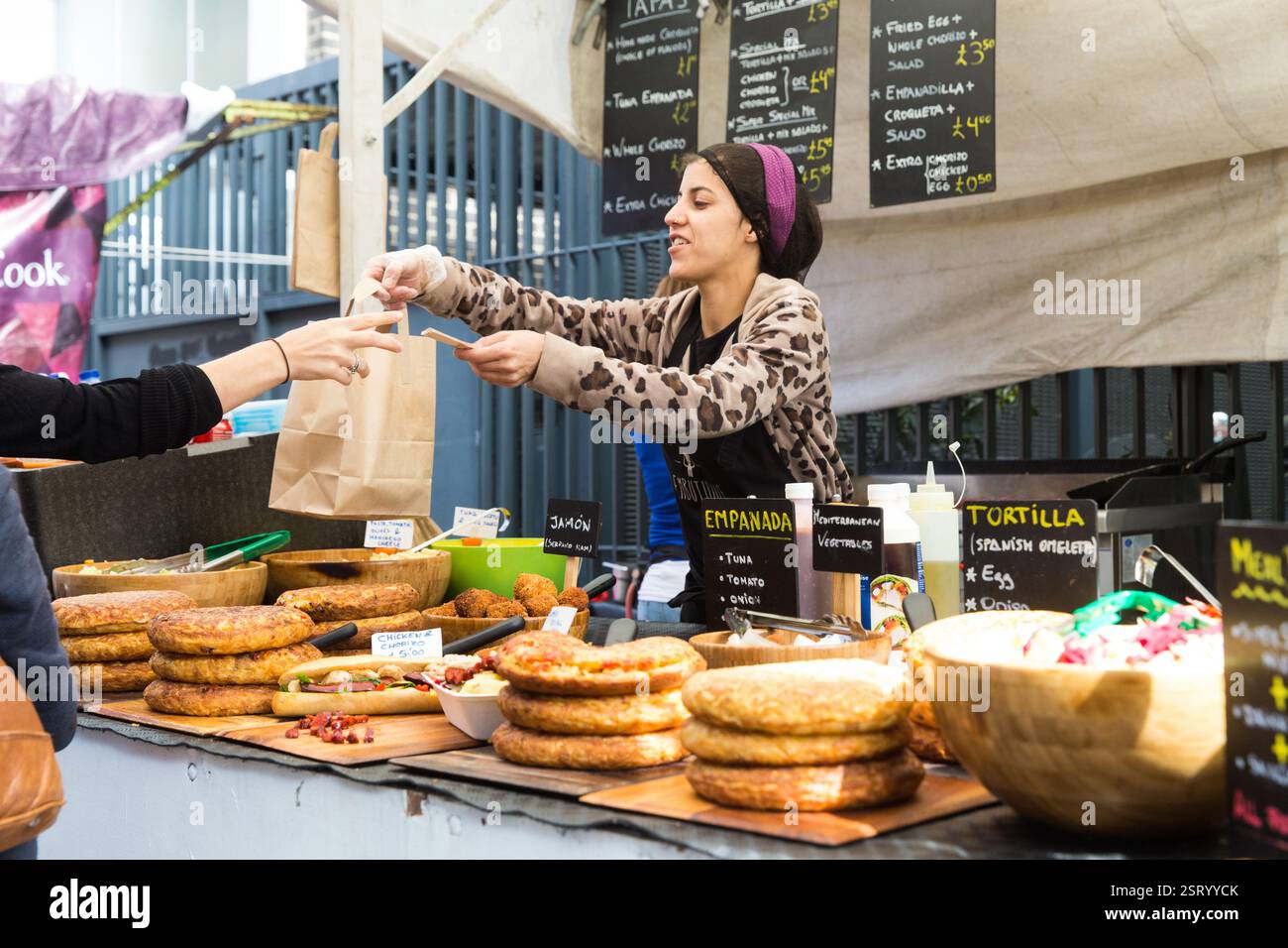 Customer paying for food at a street food stall in Leather Lane Market ...
