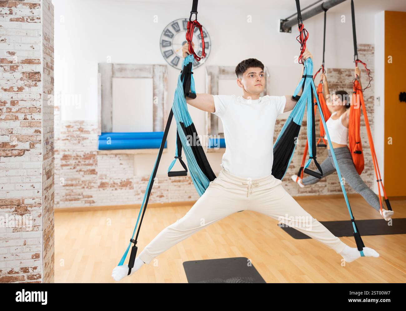 Man visitor performs exercises in hanging position on Pilates slings ...