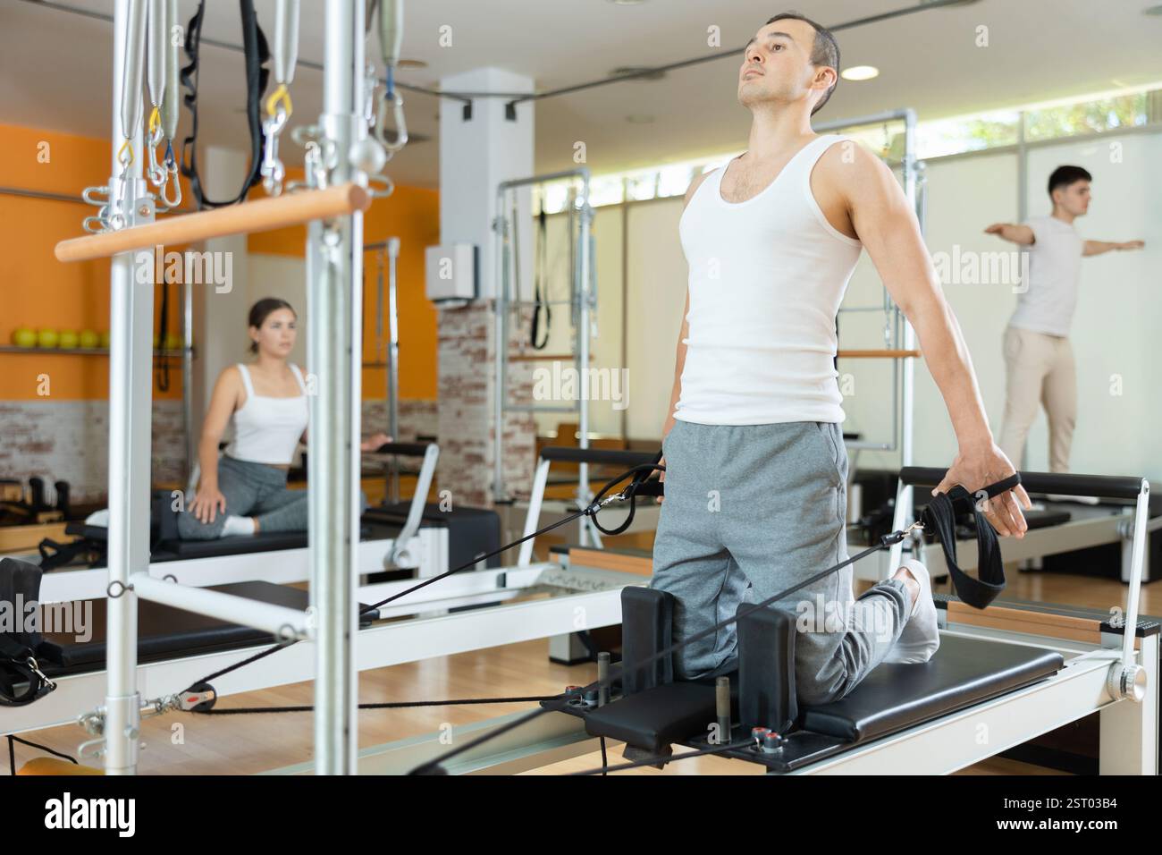 Man in gym with help of rope reformer performs exercises to strengthen ...