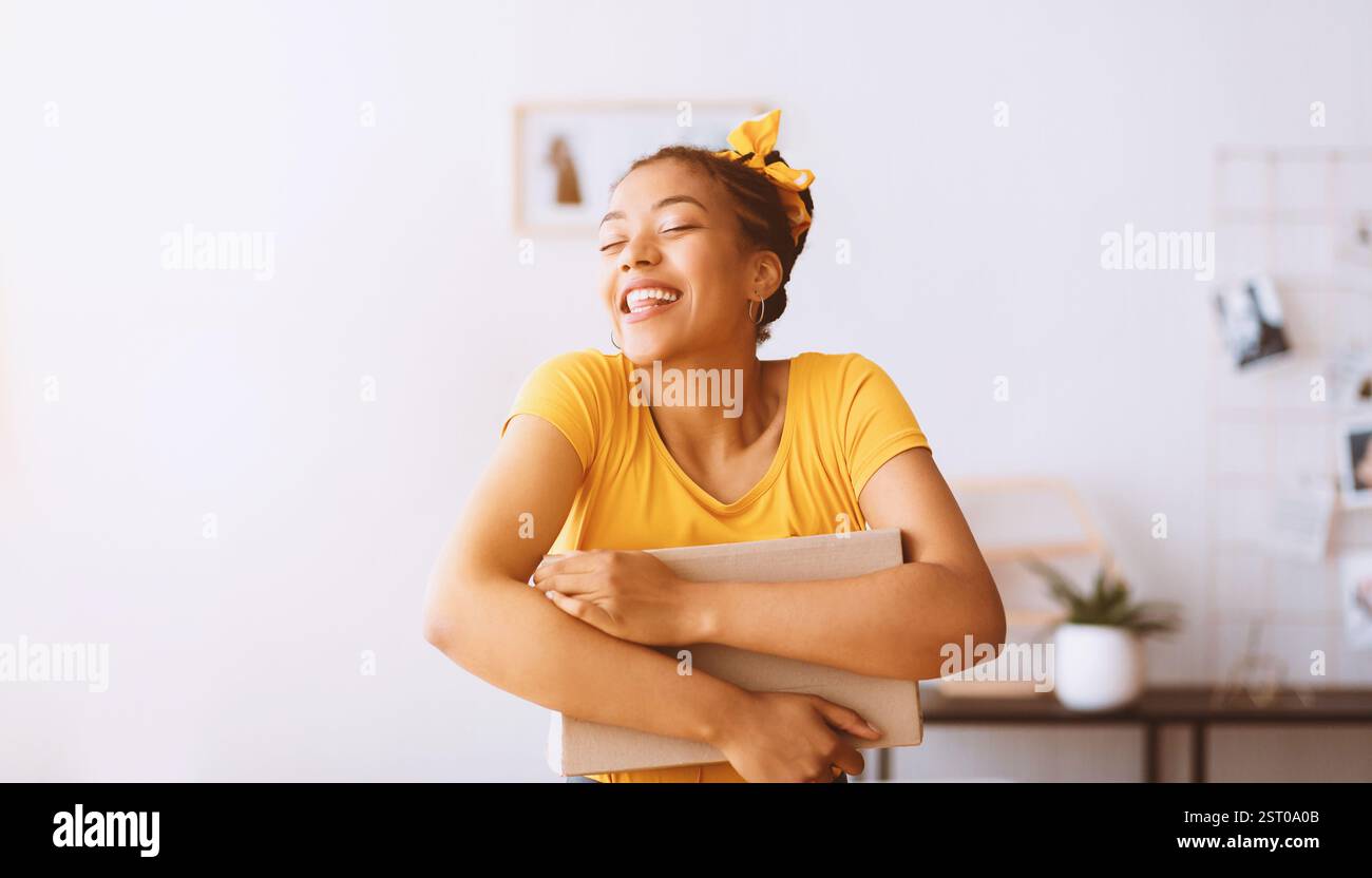 Excited black woman hugging and embracing carton box Stock Photo - Alamy